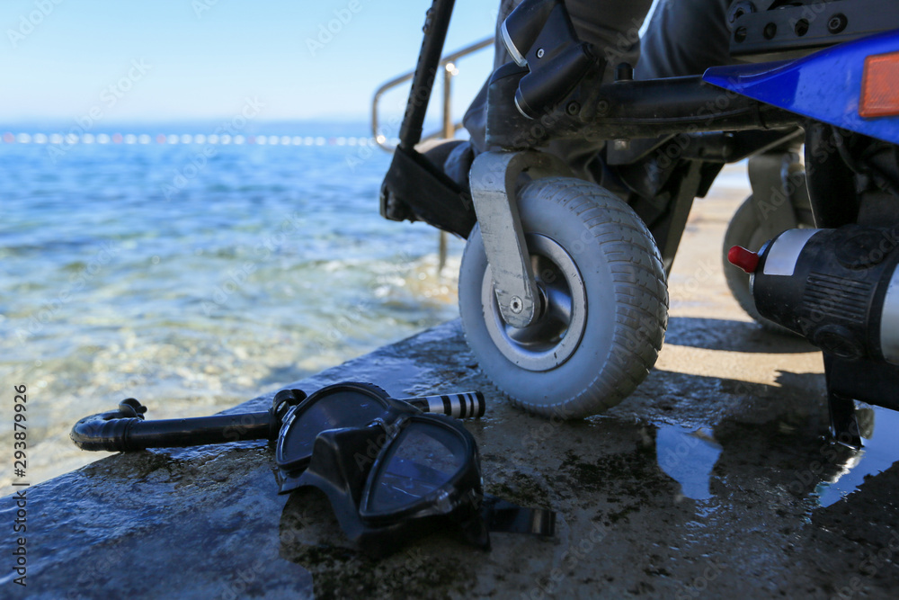 Handicapped disabled scuba diver with equipment on a beach shore ...