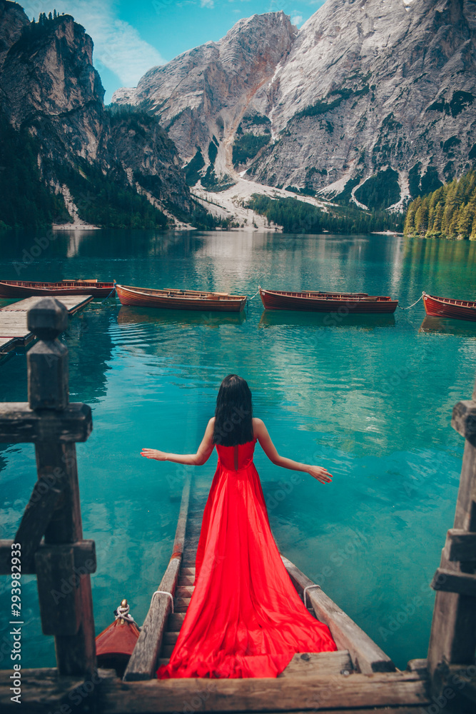 Lady in red long dress on the background of the turquoise lake with ...
