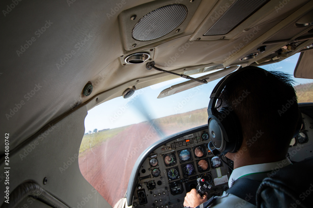 Pilot in a small airplane cockpit landing on a rural dirt airstrip ...