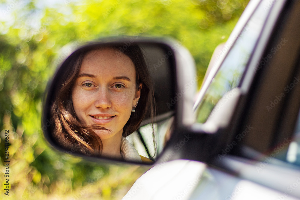 Beautiful young woman driver are looking in car side view mirror ...