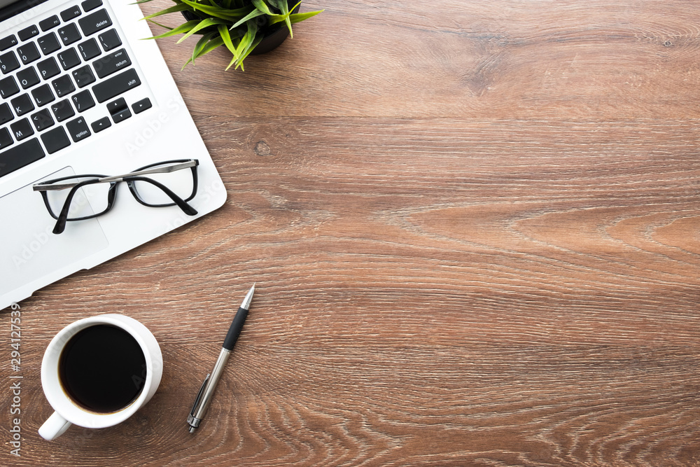 Wood office desk table with laptop computer, cup of coffee, pen and ...