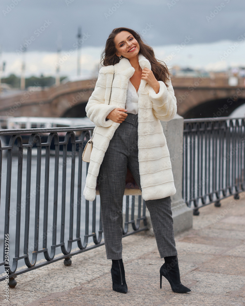 Young beautiful stylish woman walking down the street on a cold winter ...