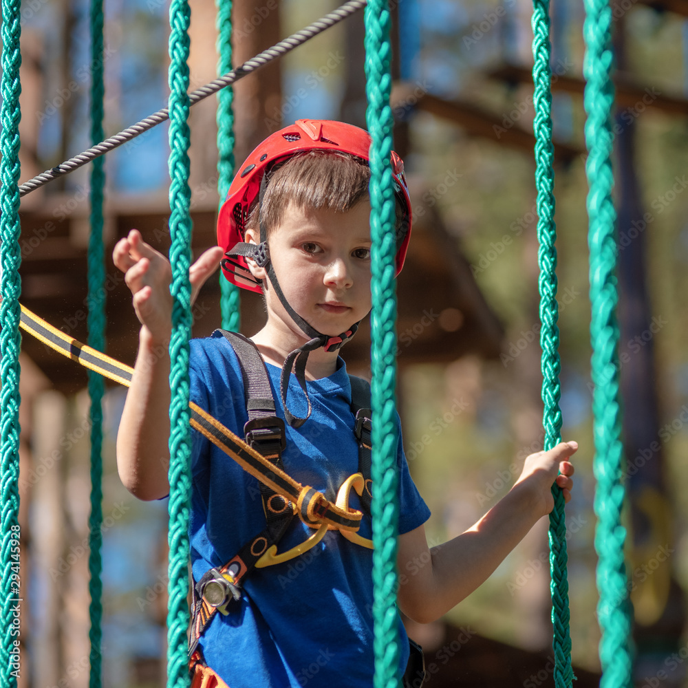 Boy enjoying activity in climbing adventure park at sunny summer day ...
