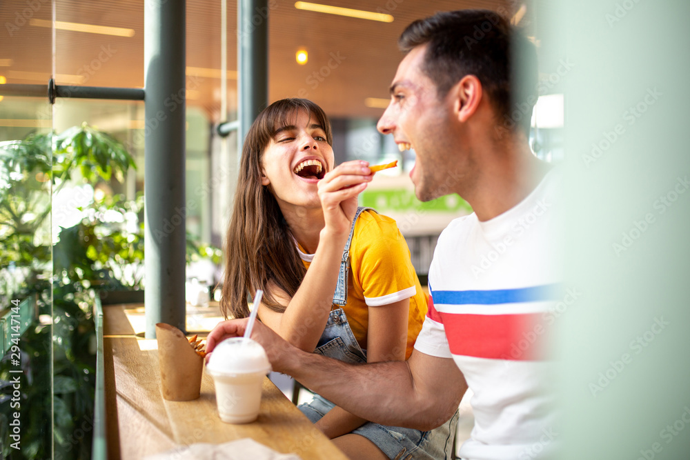 fun couple sitting at restaurant and eating food together Stock Photo ...