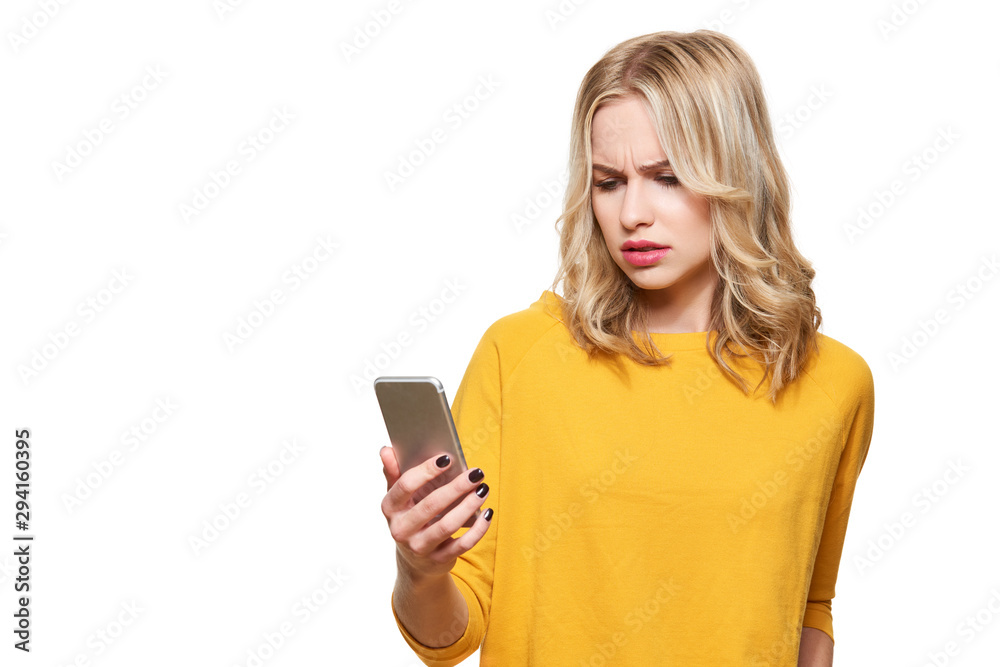 Shocked angry young woman looking at her mobile phone in disbelief ...