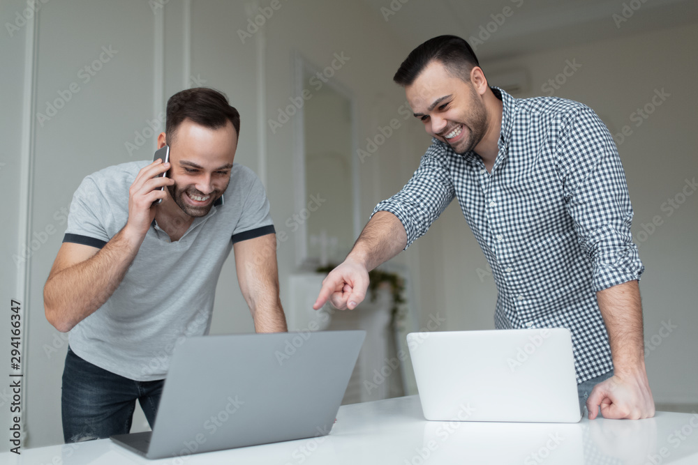 Portrait of two self-confident businessman working at laptop. One man ...