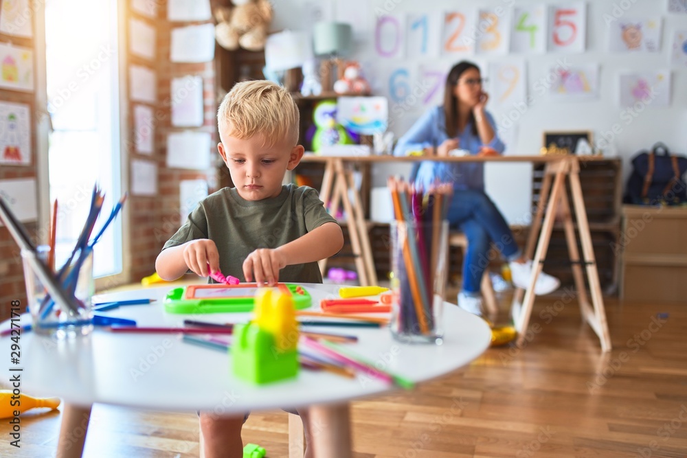 Young caucasian child playing at playschool with teacher. Mother and ...