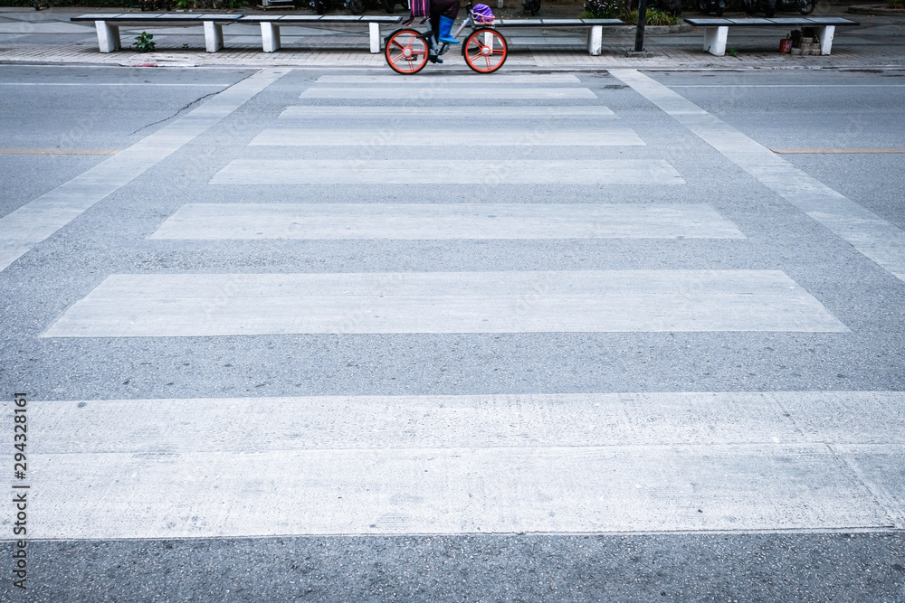 Bicycle riding pass a crosswalk in the urban street. Crosswalks are ...