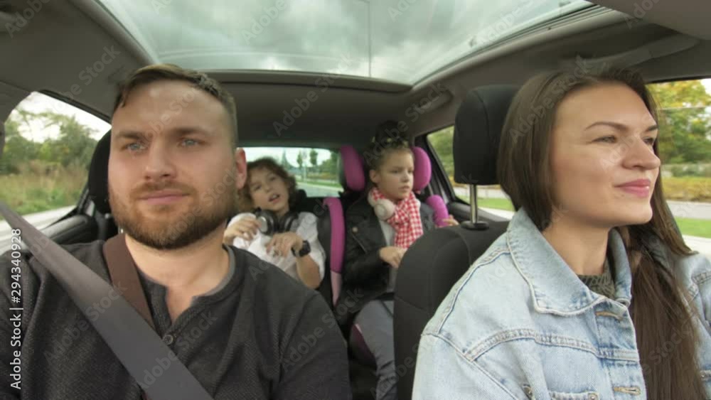 Man and woman with children driving in car, two parents and children ...