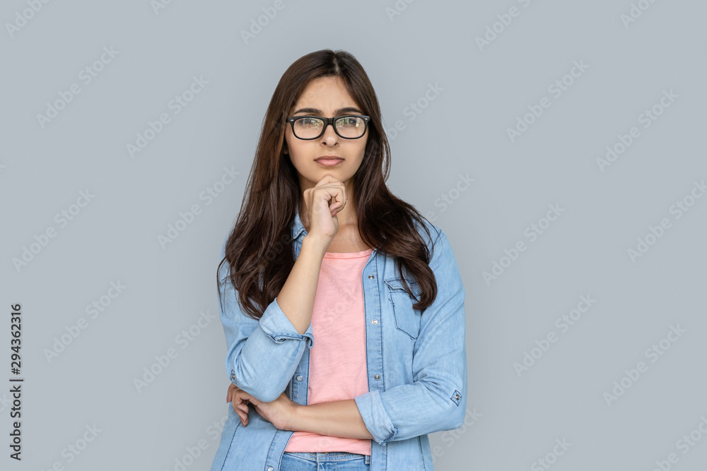Puzzled uncertain young adult woman looking at camera and standing ...