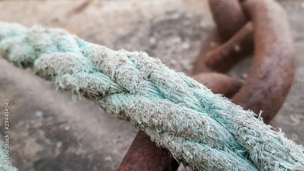 Blue colored aged boat manila rope placed on concrete road at the port ...