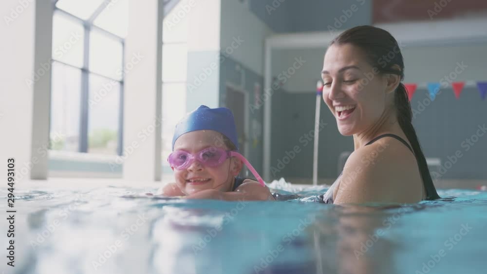 Female Swimming Coach Giving Girl Holding Float Lesson In Pool Stock ...