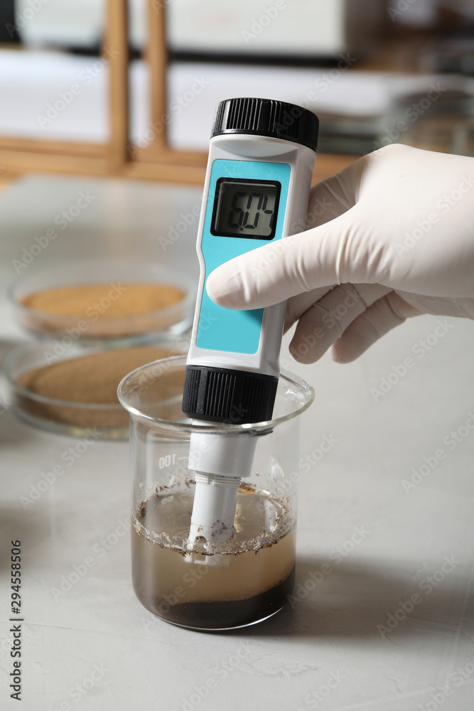 Scientist measuring acidity and pH of soil at table, closeup ...
