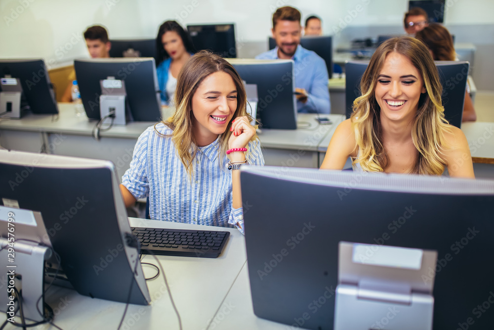 College students sitting in a classroom, using computers during class ...