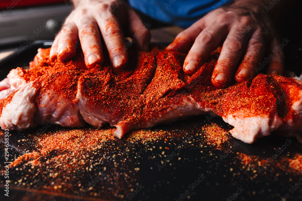 Man preparing raw piece of meat, rubbing different spices and herbs in ...