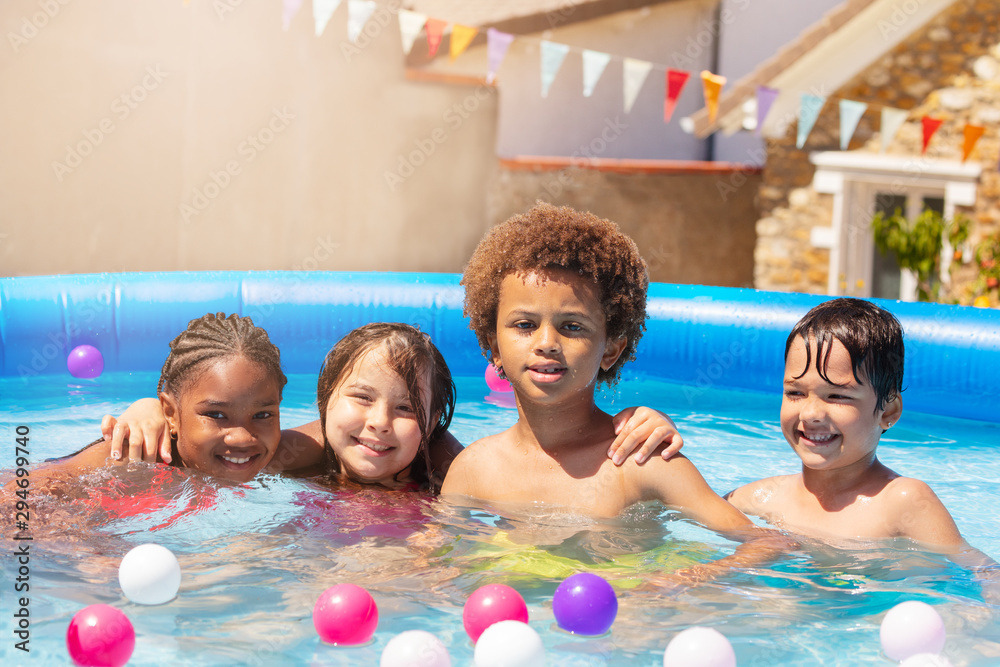 Foto de Four happy children hug sit smile in swim pool do Stock | Adobe ...