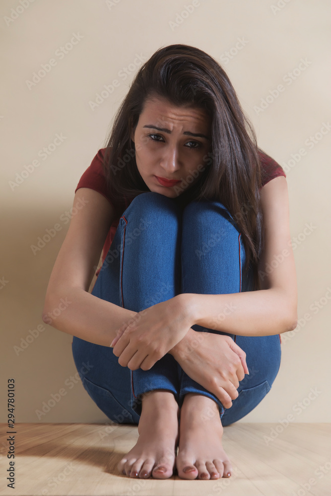 Young girl sitting alone in distress Stock Photo | Adobe Stock
