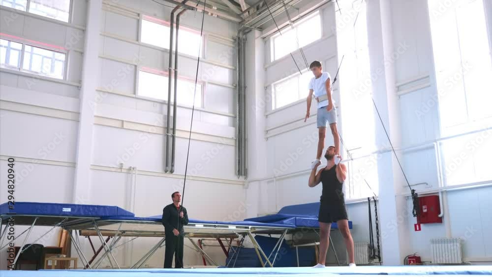 A slow motion of a young teenager athlete doing an air back flip on ...