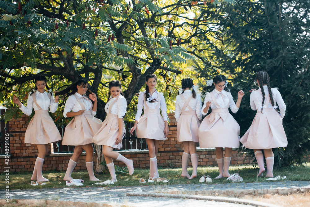 Happy schoolgirls celebrate, waving hands, dancing and cuddling ...