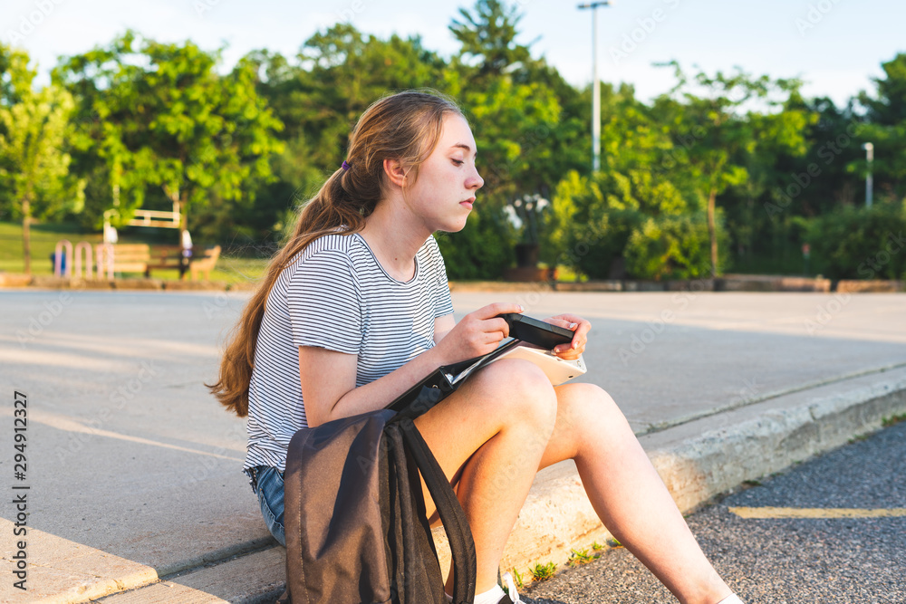 Depressed/Sad teen girl sitting on a curb in front of a high school ...