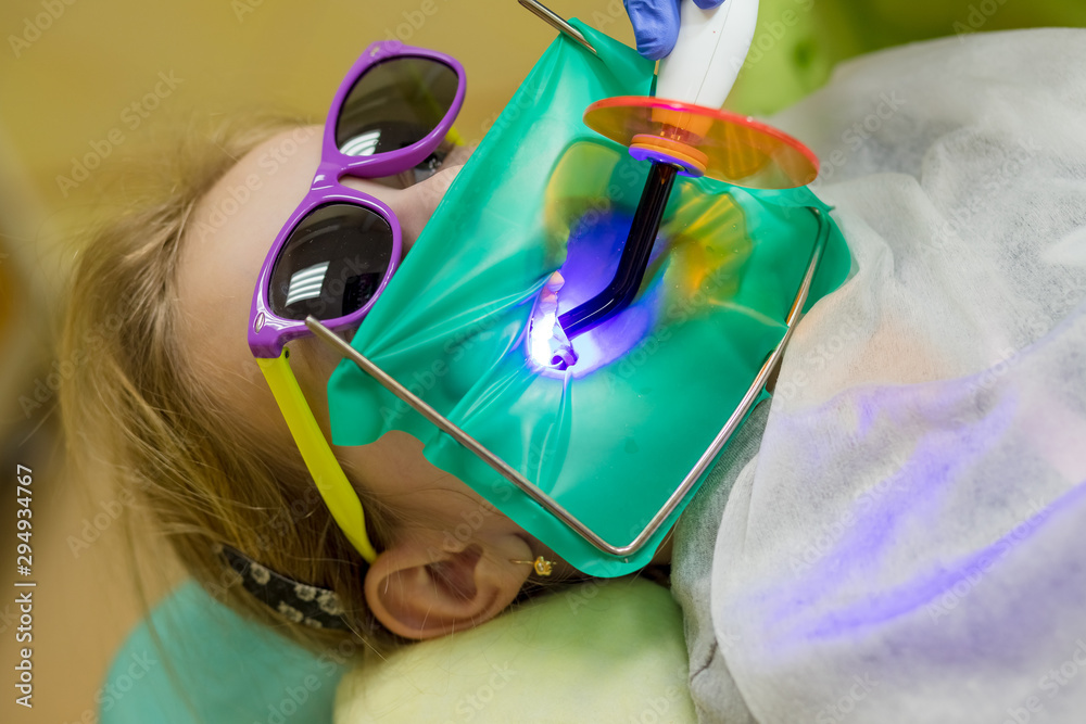 Dentist performing dental filling procedure to preteen girl in ...