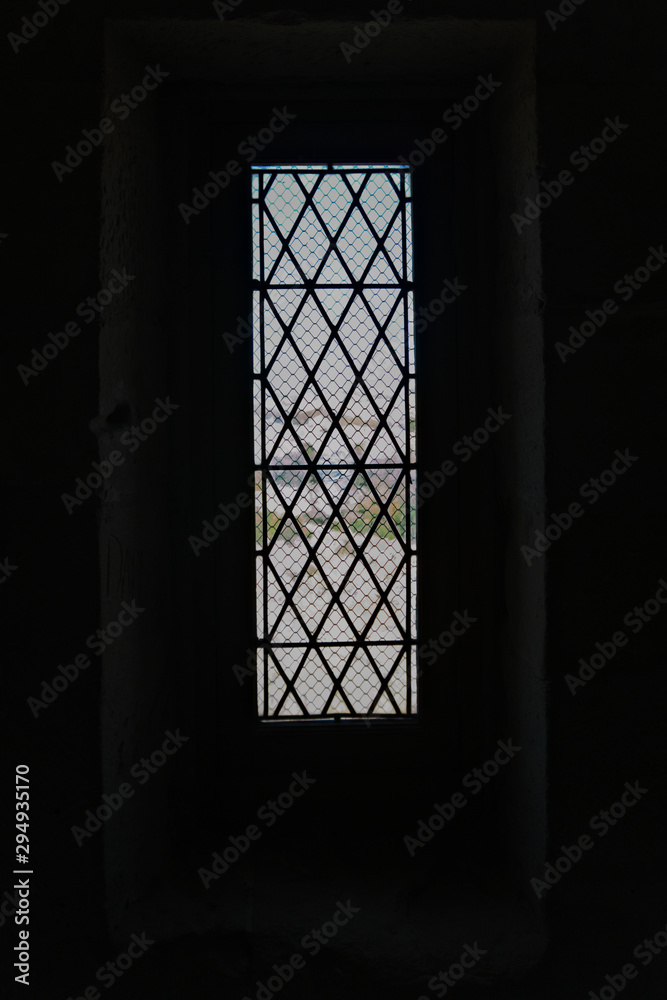 Looking out of a barred window in a dark room of a medieval castle ...