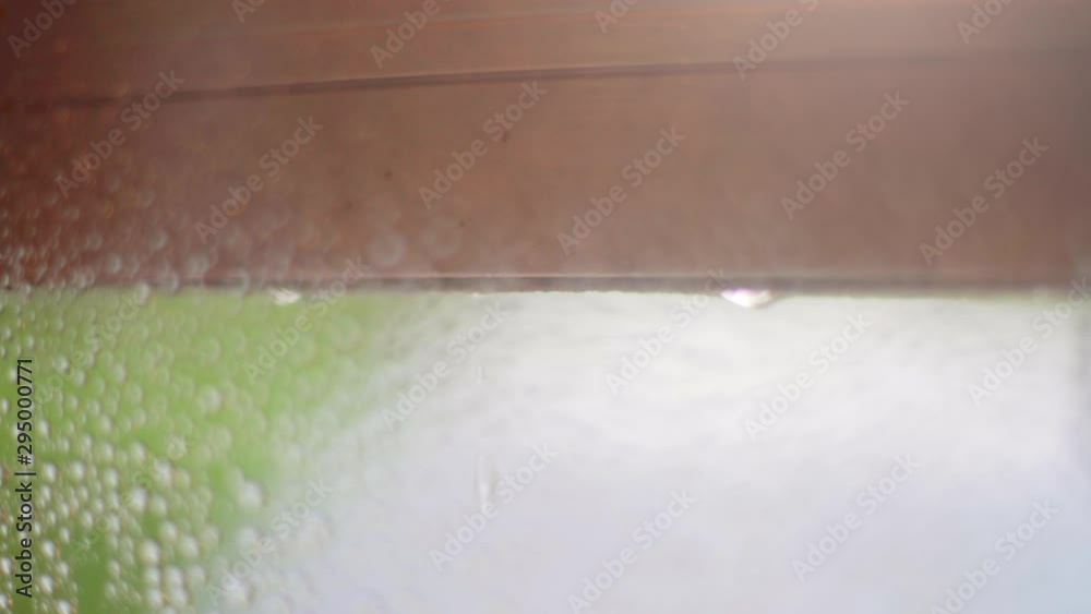 4K Slow Motion super close up of a water drop falling from a window ...