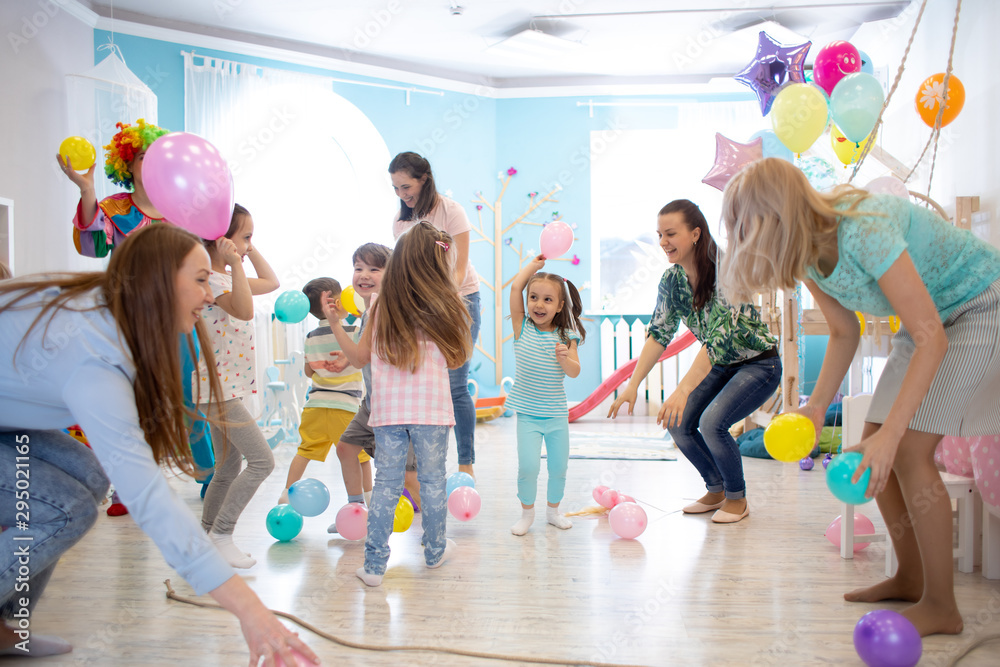 Jolly little kids and parents playing together on birthday party in ...