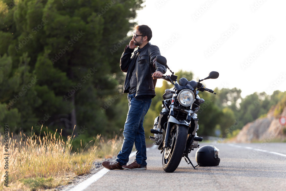 Man biker talking on the phone to the insurance of his motorcycle after ...