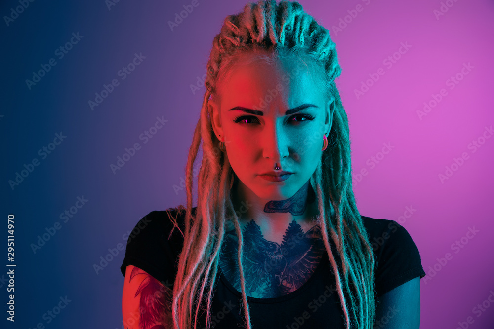 Caucasian young woman's portrait on gradient background in neon light ...