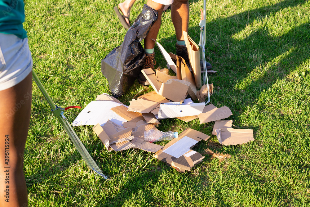 Volunteer picking up rubbish from lawn. Legs of man gathering paper ...