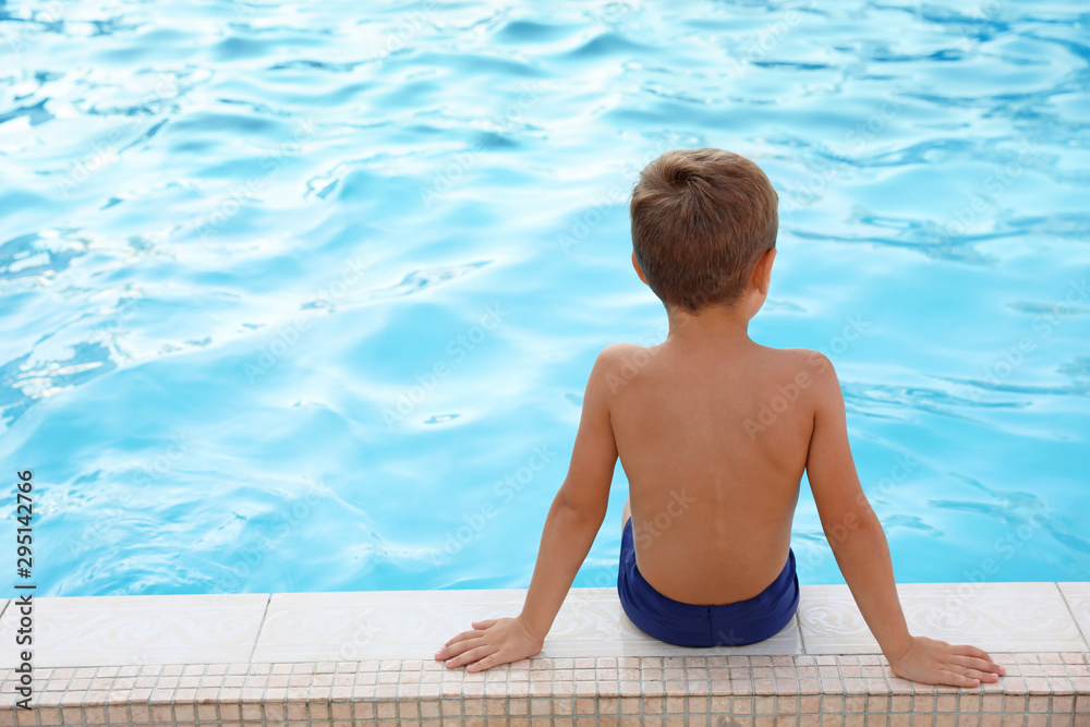 Cute little boy sitting near outdoor swimming pool Stock Photo | Adobe ...