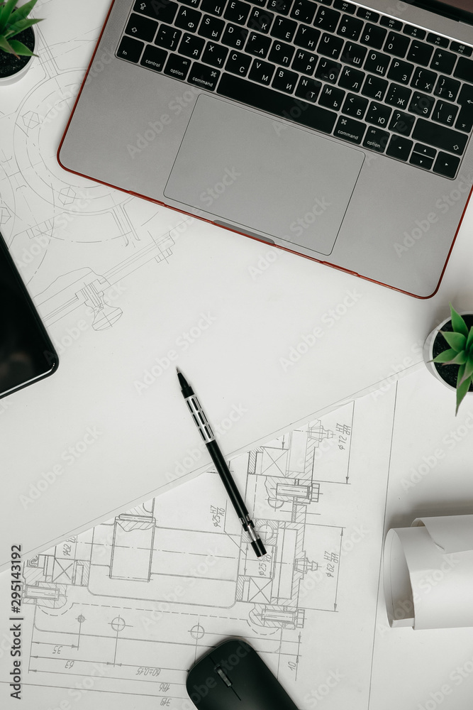 Laptop, phone and rolls of drawings on the Desk in engineering ...