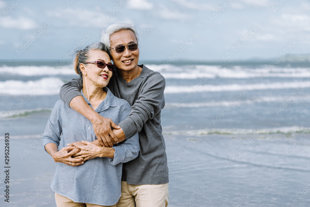 Asian Senior Couple Or Elderly People Walking And Siting At The Beach