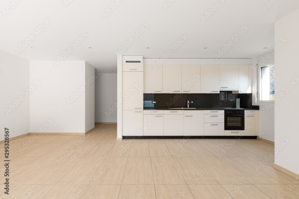 Empty room with white walls, travertine floor and white kitchen and ...