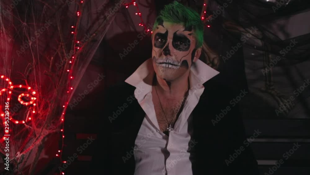 Halloween concept. Face of a demon smokes and looks into the frame with ...