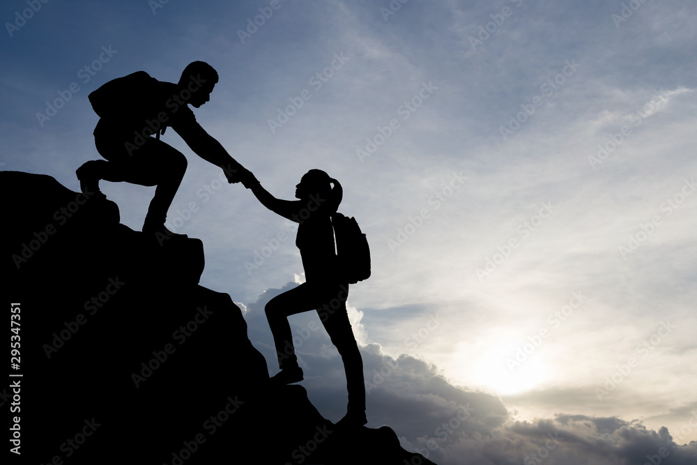 Poster Silhouette of people helping each other hike up a mountain at ...