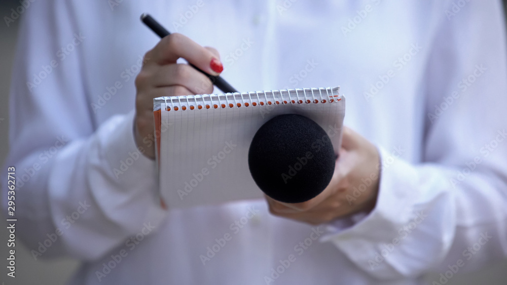 Journalist with microphone writing data in notebook, preparing ...