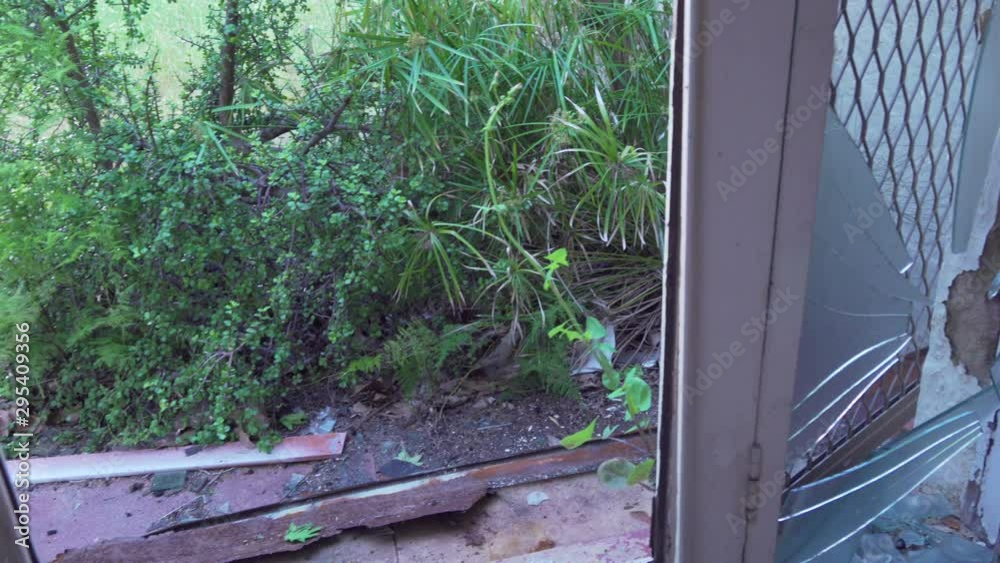 Pan across rubbish on lounge room floor of abandoned, derelict house ...