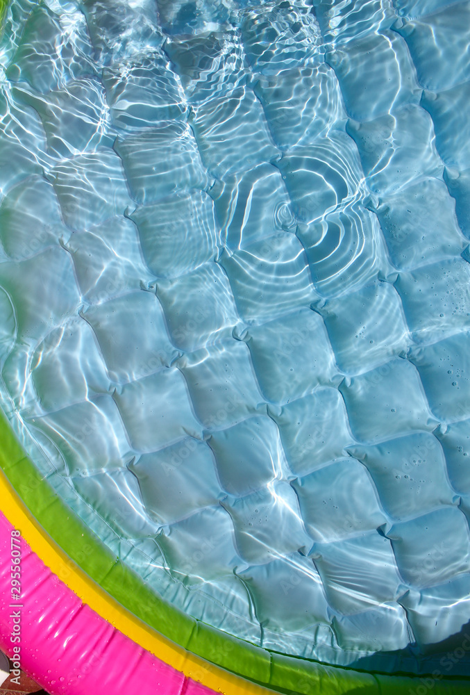 Bright blue inflatable paddling pool surface with water ripples. Summer ...