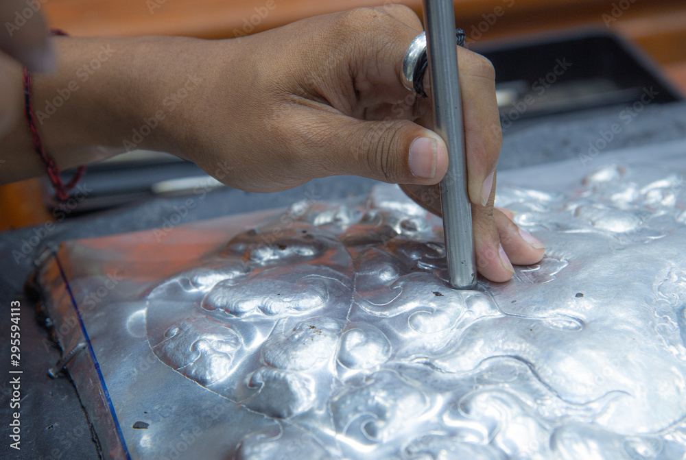 Man artisan hand holding tool making extraordinary silver plate carving ...