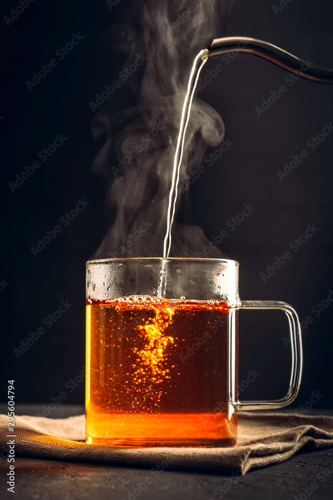 The process of brewing tea, pouring hot water from the kettle into the ...