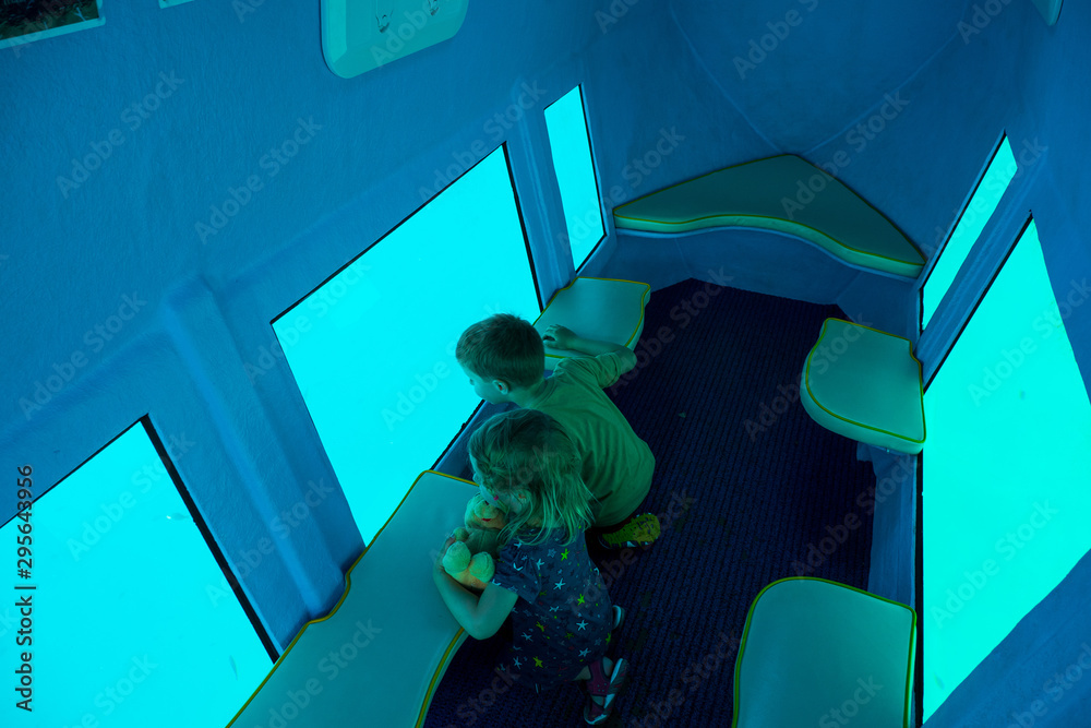 3 and 5 years old kids looking through the window of a glass bottom ...