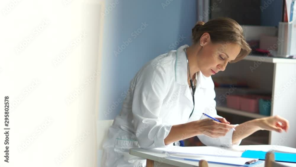 Medicine and healthcare concept. A lovely mature female doctor fills ...