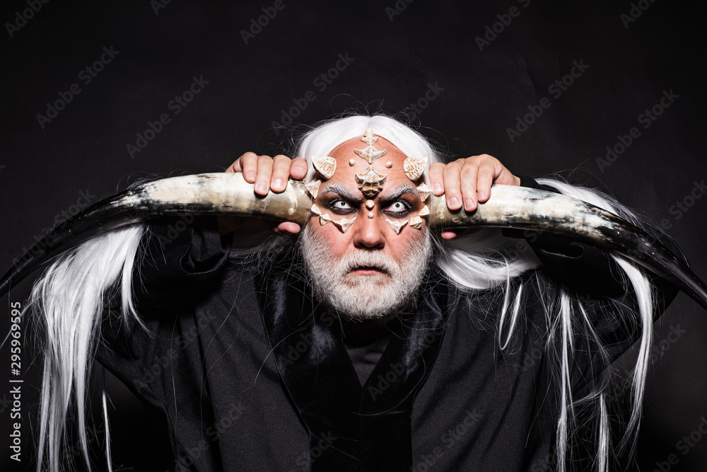 Bearded old man dressed like Halloween monster. Elderly man holding two ...