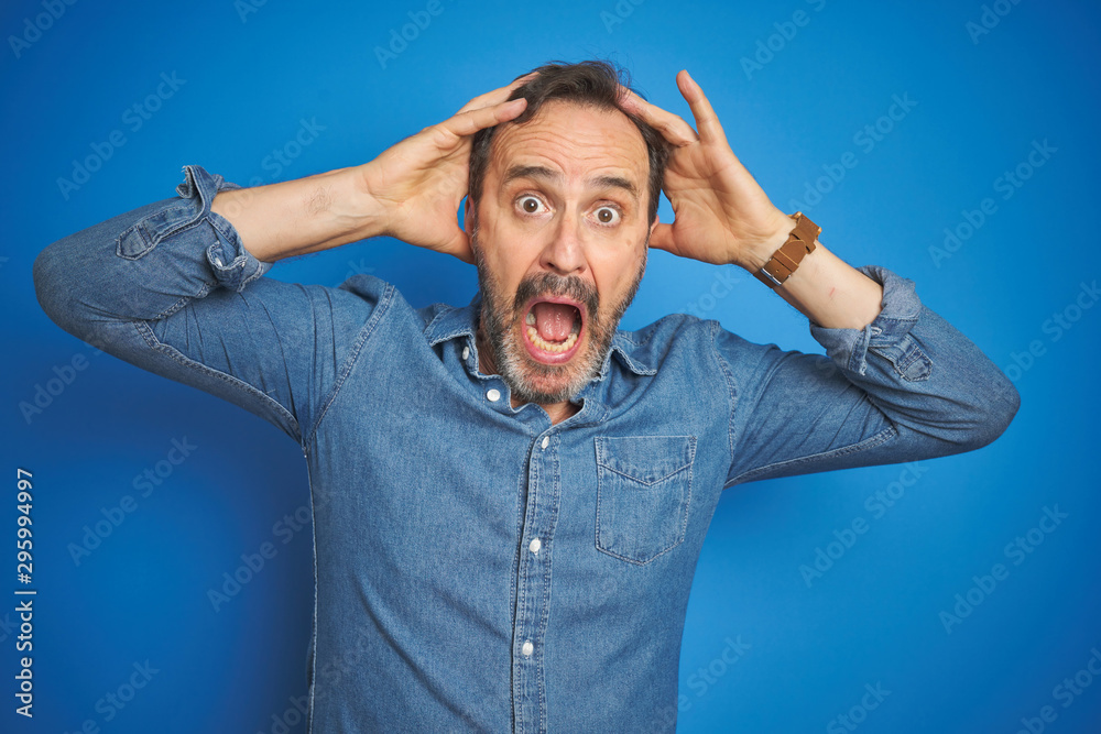 Handsome middle age senior man with grey hair over isolated blue ...