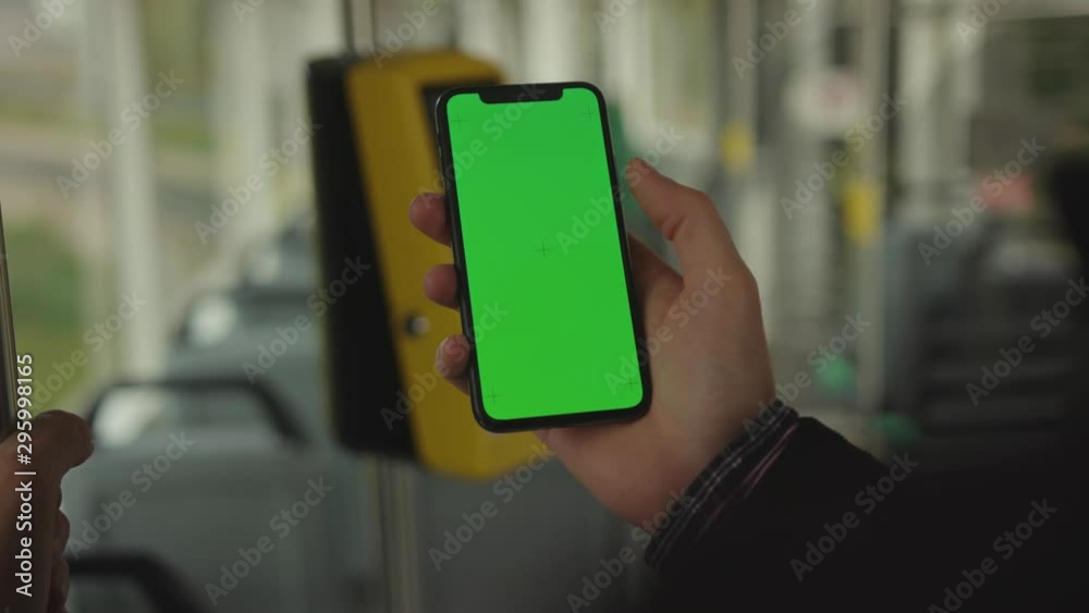 Hands man uses holding a mobile phone with a vertical green screen background tram ticket ...