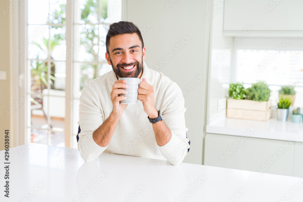 Handsome man smiling while enjoying drinking a cup of coffee in the ...