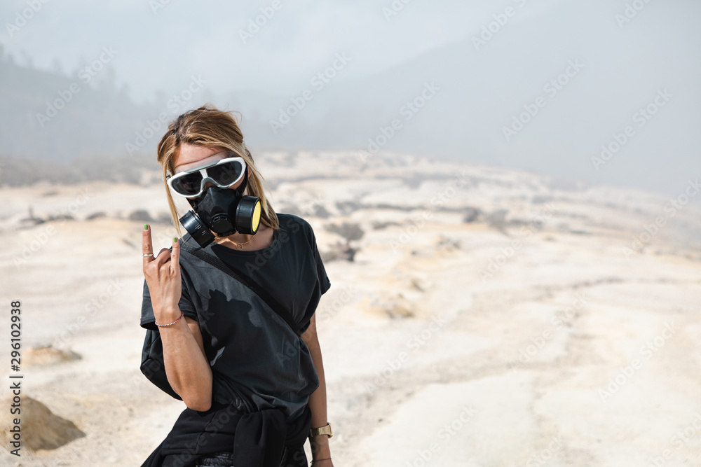 Young women in protective mask walking by wastelands around Kawah Ijen ...