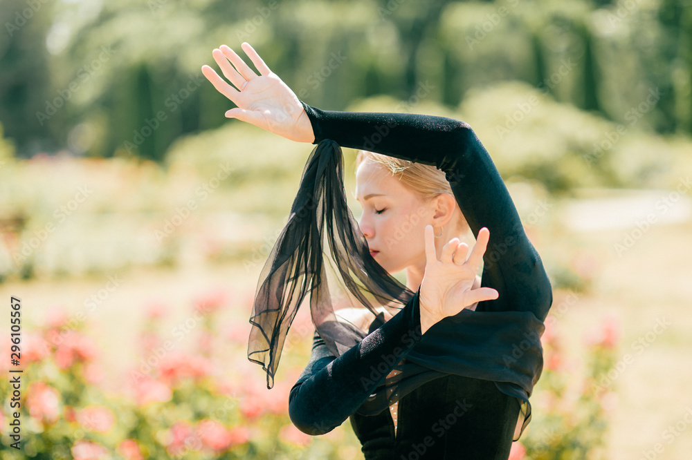 Eccentric woman in black dress with veil on her sleeve posing in summer ...